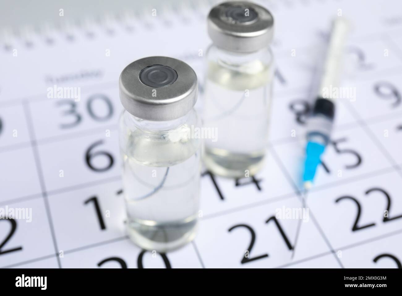 Vial and syringe on calendar, closeup. Vaccination and immunization ...