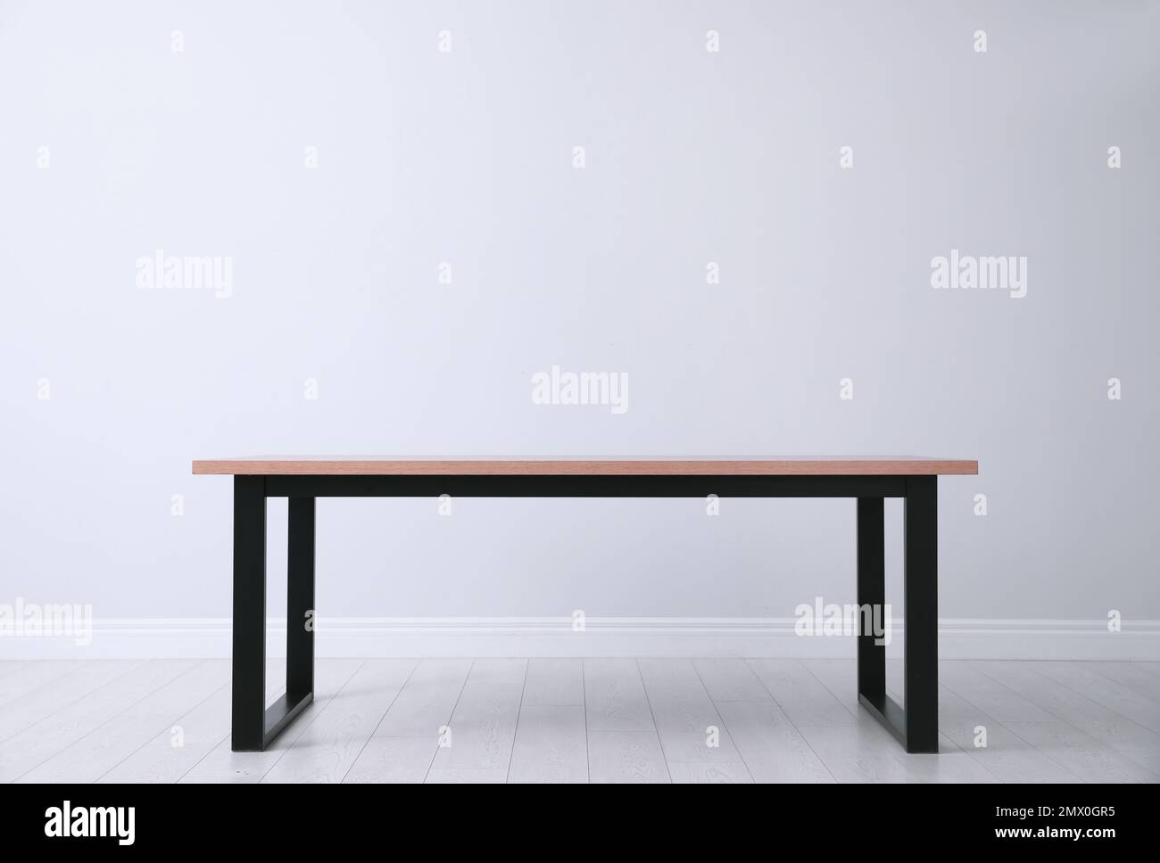 Wooden table near white wall in room, space for text. Stylish interior ...