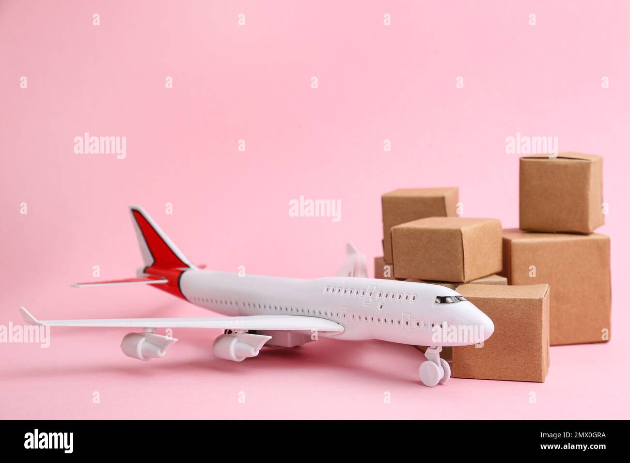 Airplane model and carton boxes on light pink background. Courier ...