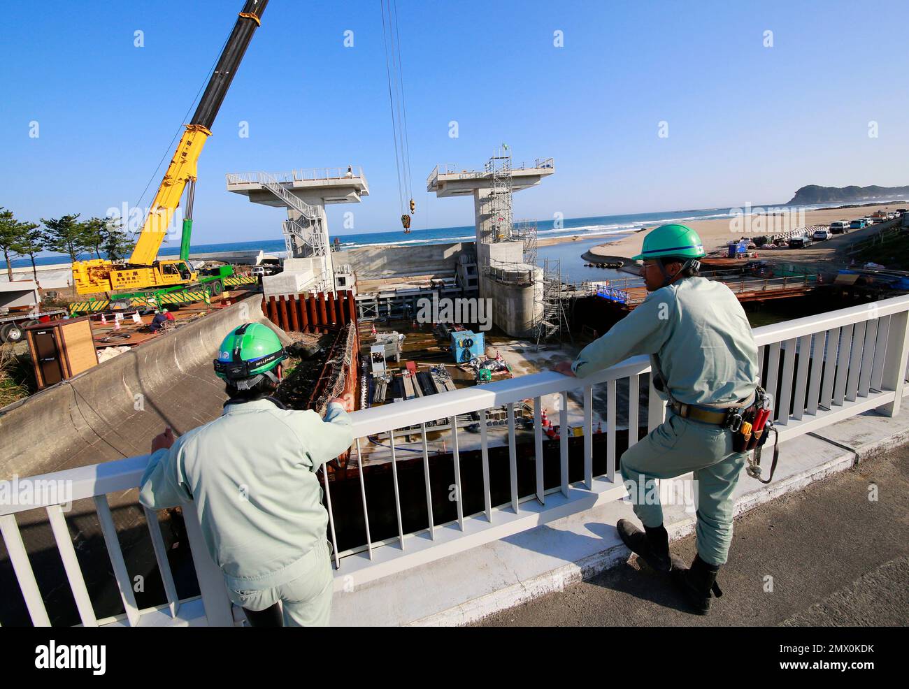 Workers look at a floodgate under construction after tsunami warning was lifted, in Iwaki ...
