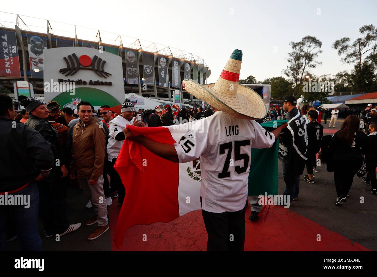 An Oakland Raiders fan carries a Mexican flag as he arrives to Azteca ...