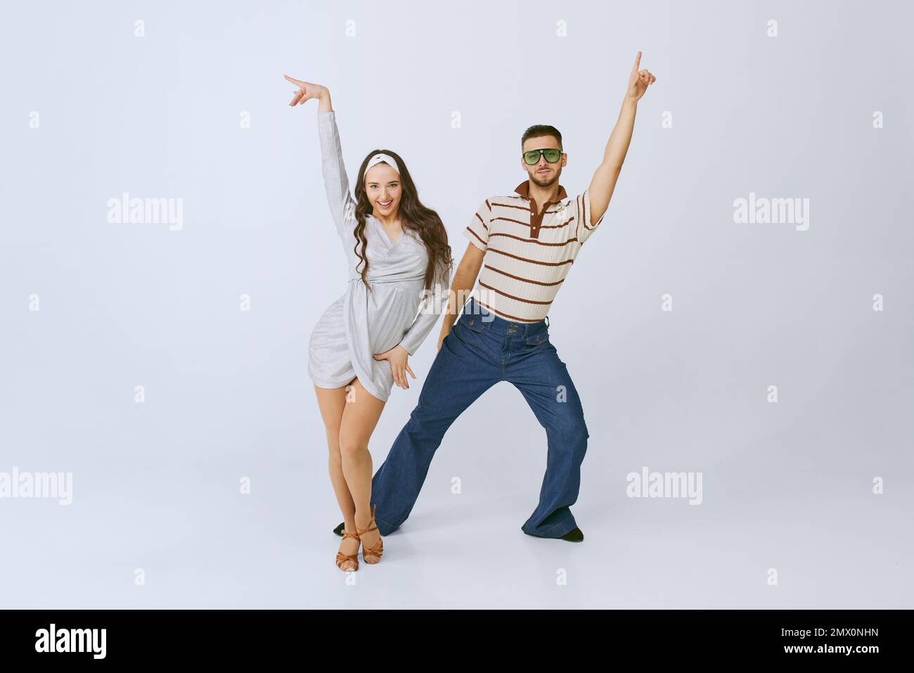Happiness. Young beautiful girl in silver dress and stylish man dancing ...