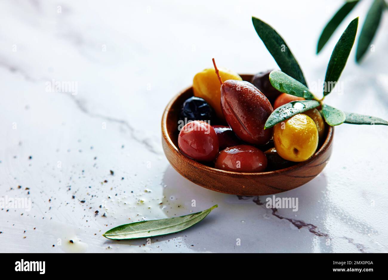 Assorted types of fresh pickled olives with leaves served in wooden ...