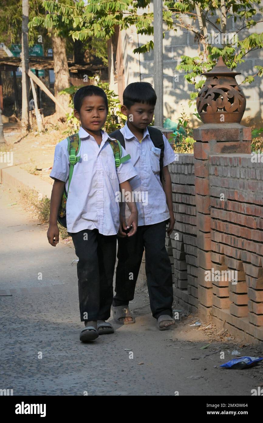 Two kids in school uniform go back to their home in a rural village ...
