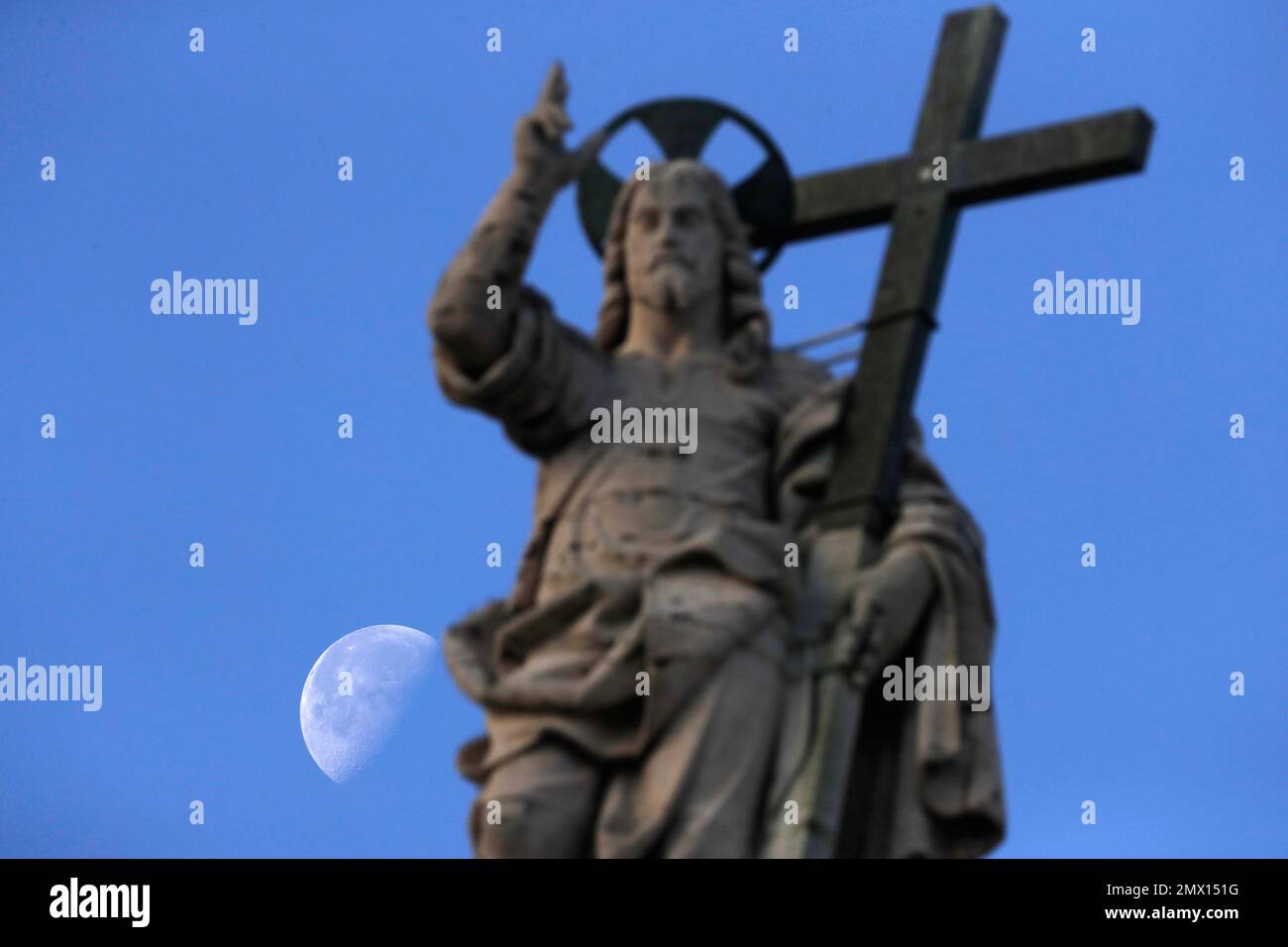 The moon sets behind the statue of Jesus atop the facade of St. Peter's ...