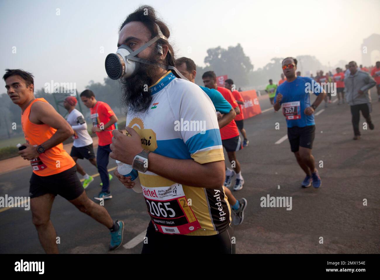 A participant wears a gas mask as he runs during the Delhi Half ...