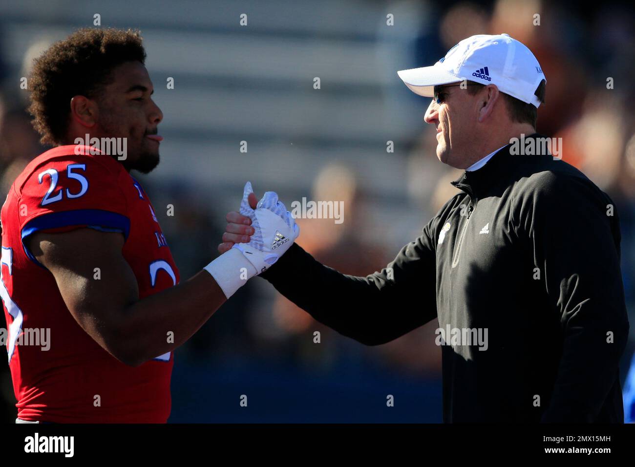 Kansas senior running back J.J. Jolaoso (25) shakes hands with head ...