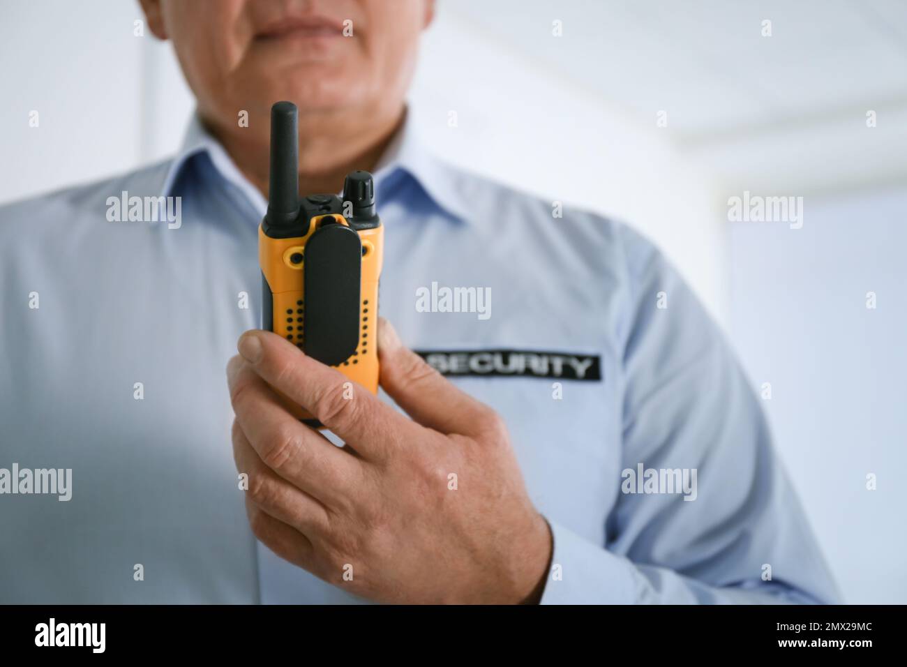 Professional security guard with portable radio set indoors, closeup ...