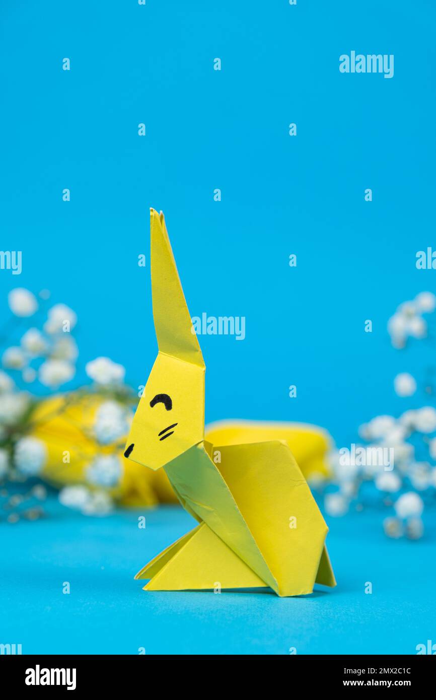 A yellow origami rabbit on a blue background. Crafts for Easter, fold ...