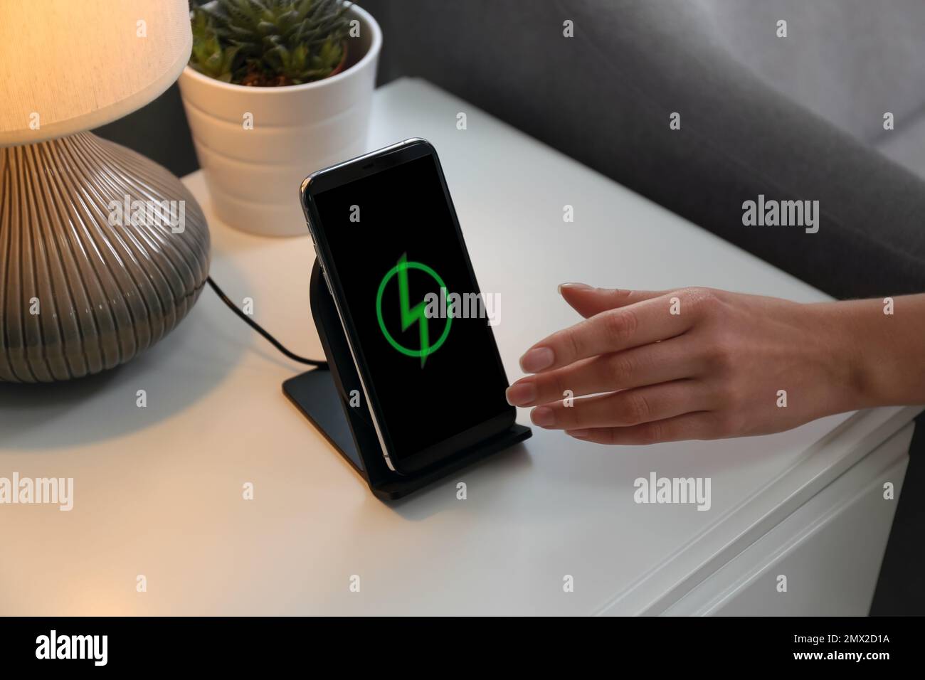 Woman taking smartphone from wireless charger in room, closeup Stock ...