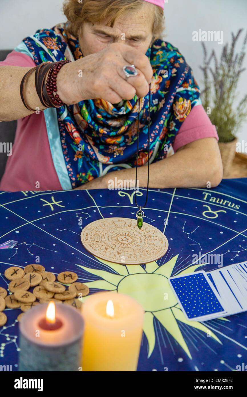 Woman fortune teller fortune telling pendulum. Selective focus. People ...
