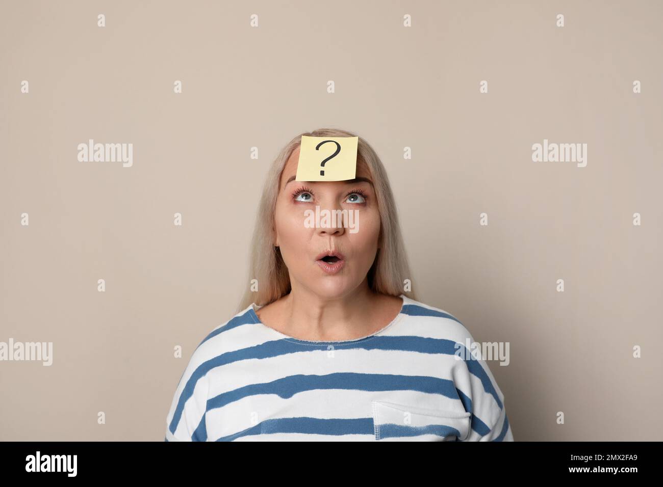 Emotional mature woman with question mark on beige background Stock ...