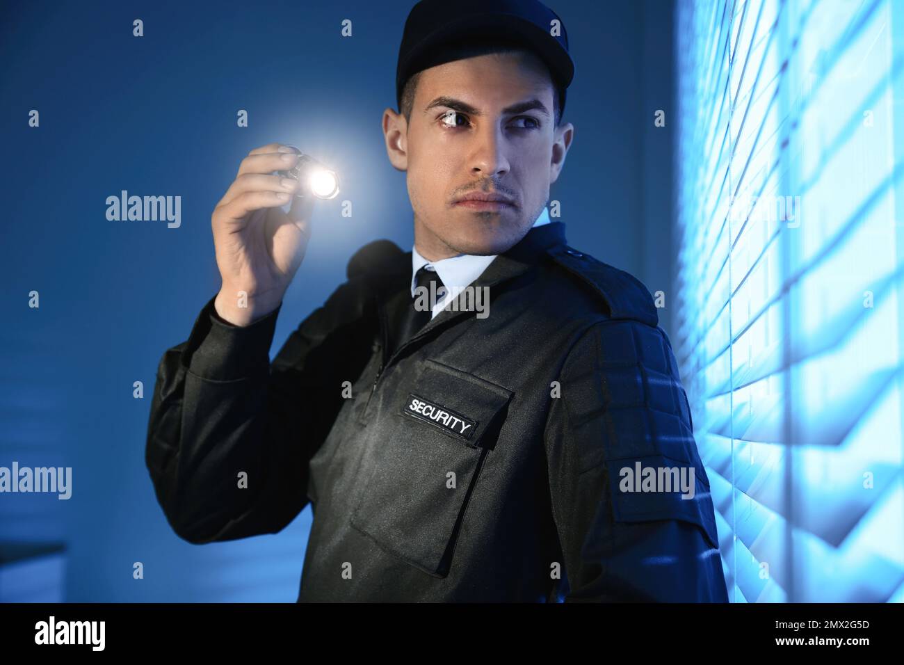 Professional security guard with flashlight near window in dark room Stock Photo - Alamy