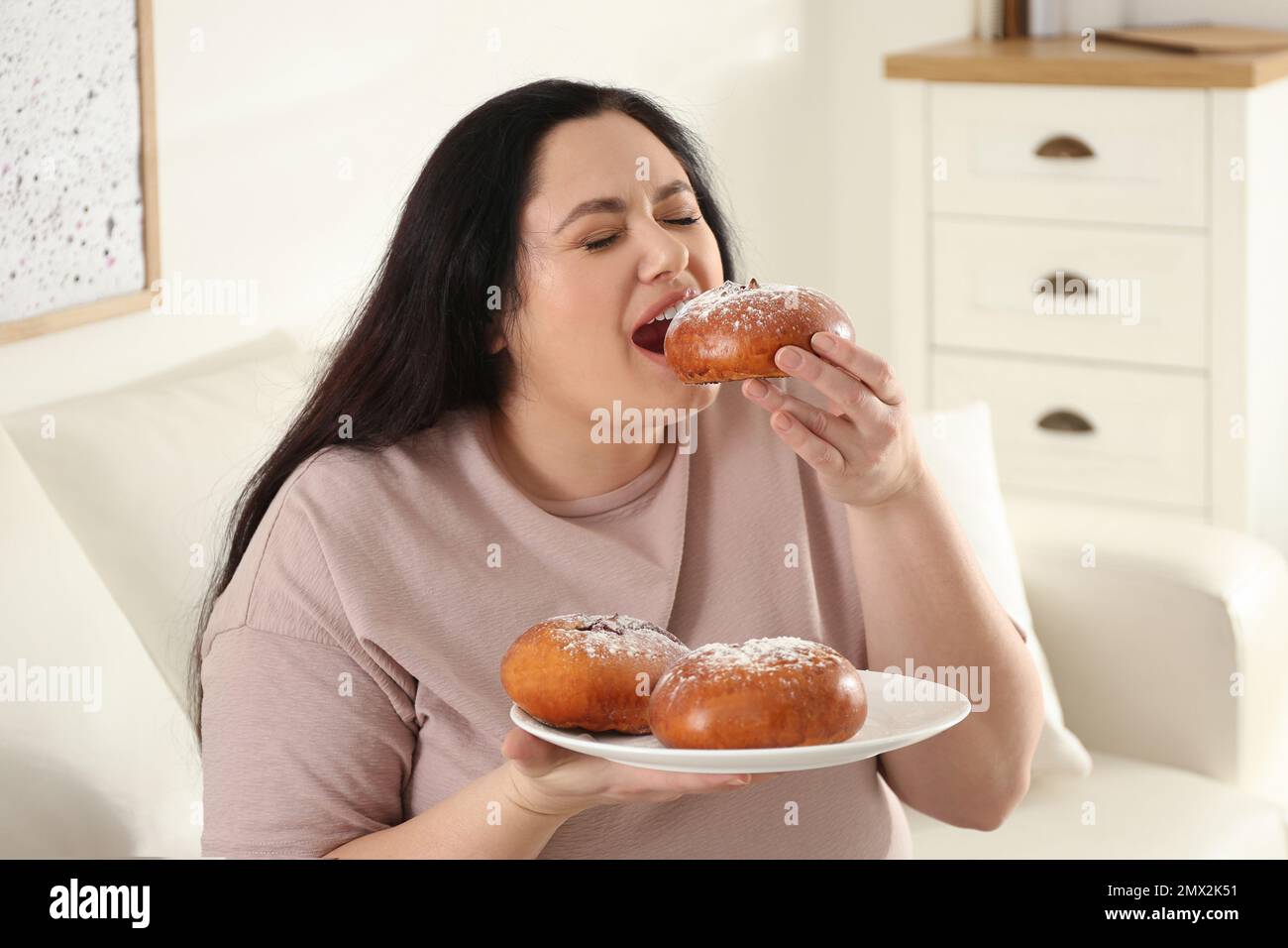 Lazy overweight woman eating buns at home Stock Photo - Alamy