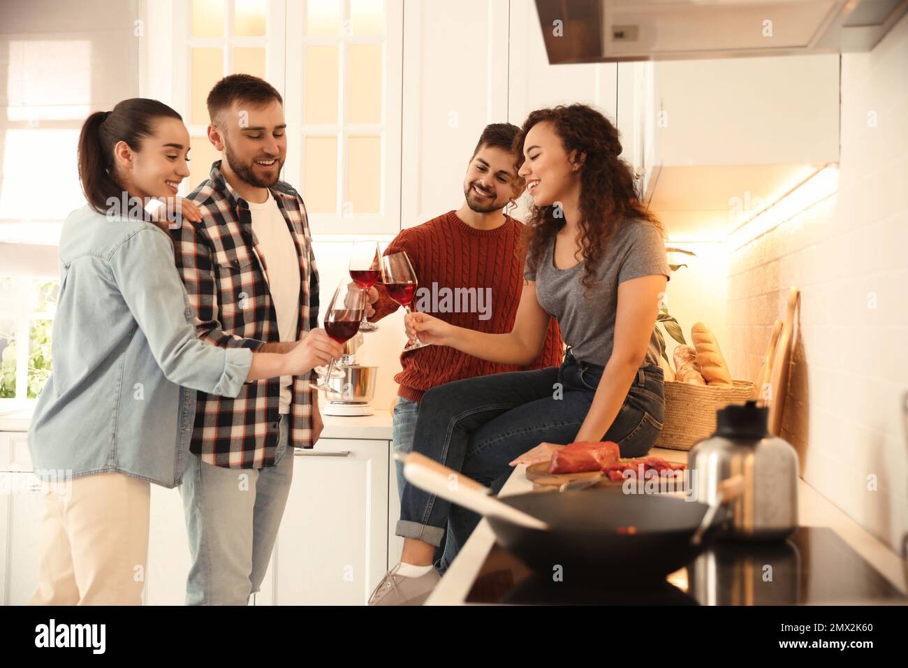 Happy people drinking wine while cooking food in kitchen Stock Photo ...