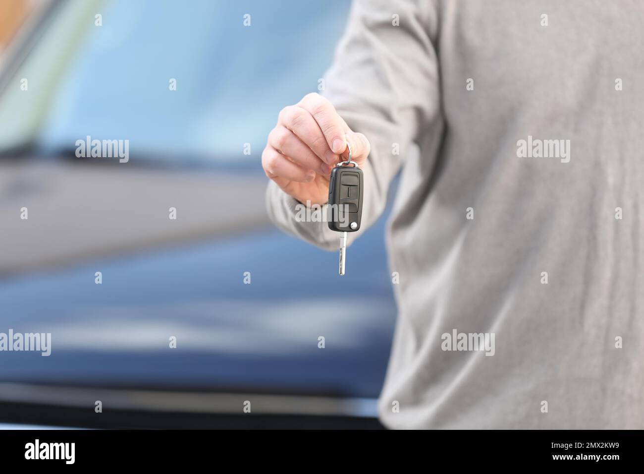 Man holding key in modern auto dealership, closeup. Buying new car ...