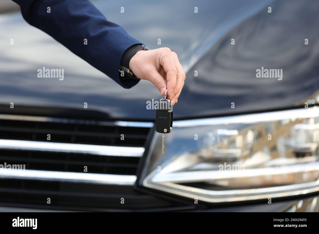Man holding key in modern auto dealership, closeup. Buying new car ...
