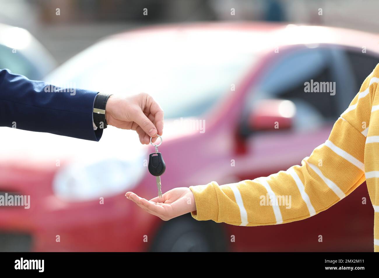 Salesman giving key to customer in modern auto dealership, closeup ...