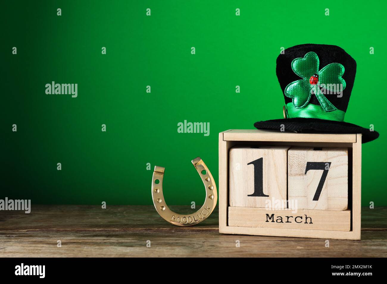 Black leprechaun hat, wooden block calendar and horseshoe on table ...