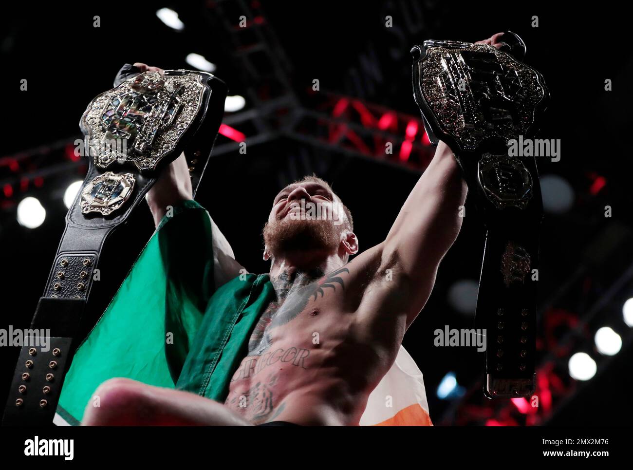 Conor McGregor holds up his title belts after he defeated Eddie Alvarez during a lightweight ...