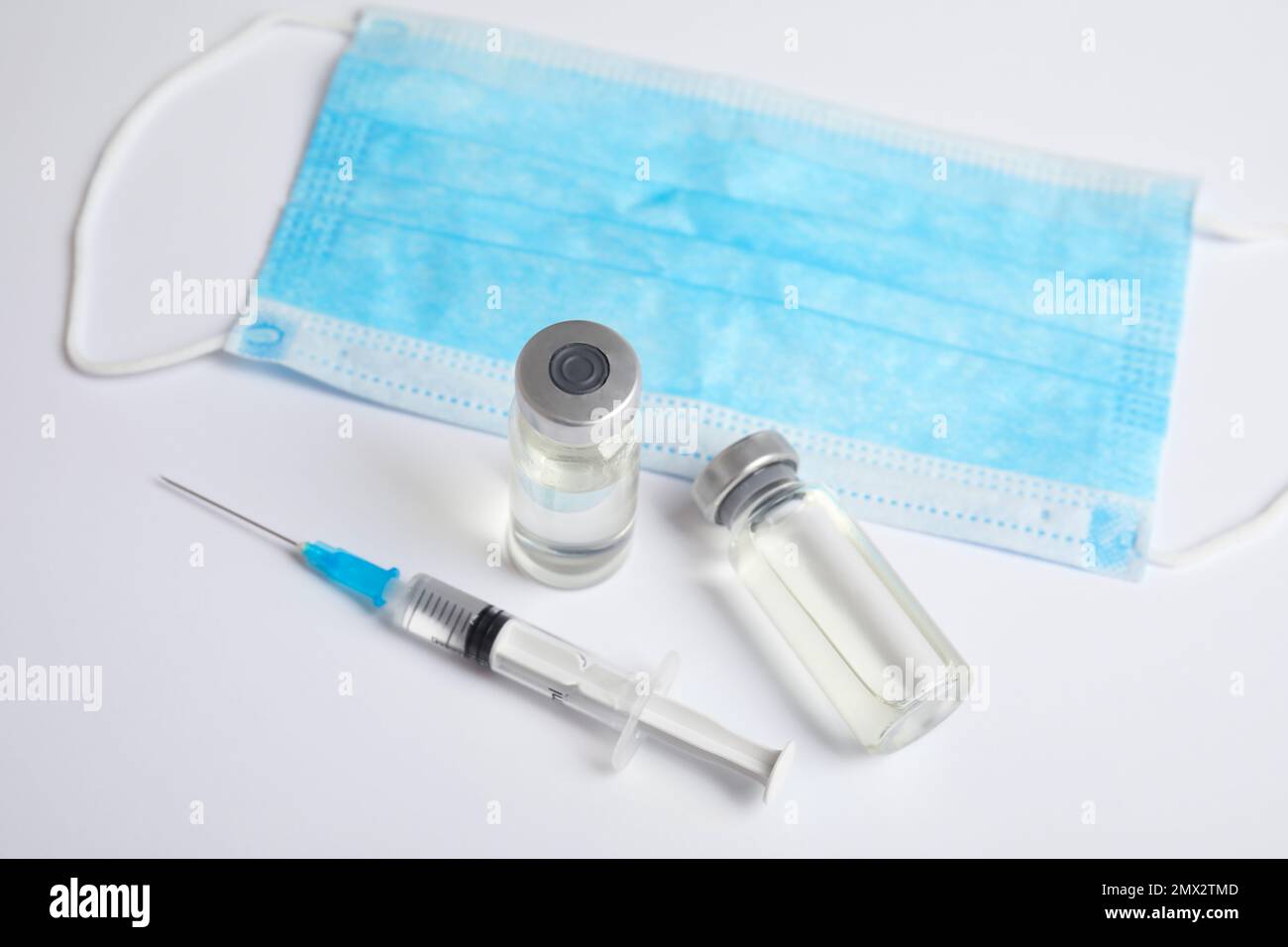 Vials, syringe and surgical mask on light background. Vaccination and ...