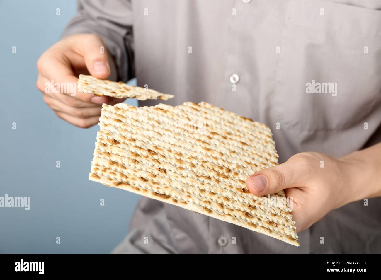 Man with Matzo on grey background, closeup. Pesach (Passover ...