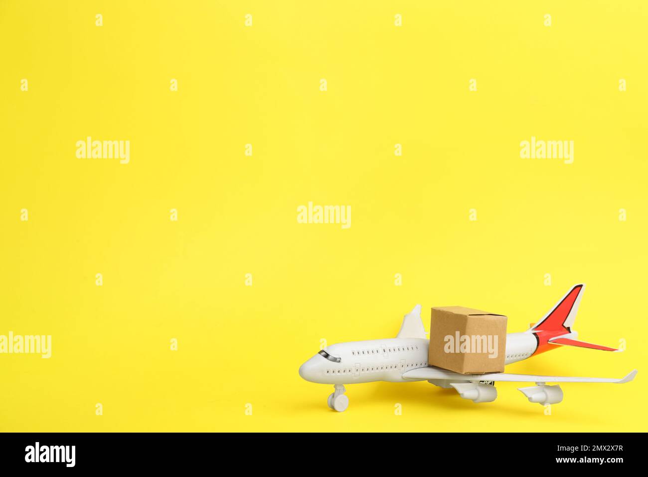 Airplane model and carton box on yellow background, space for text ...