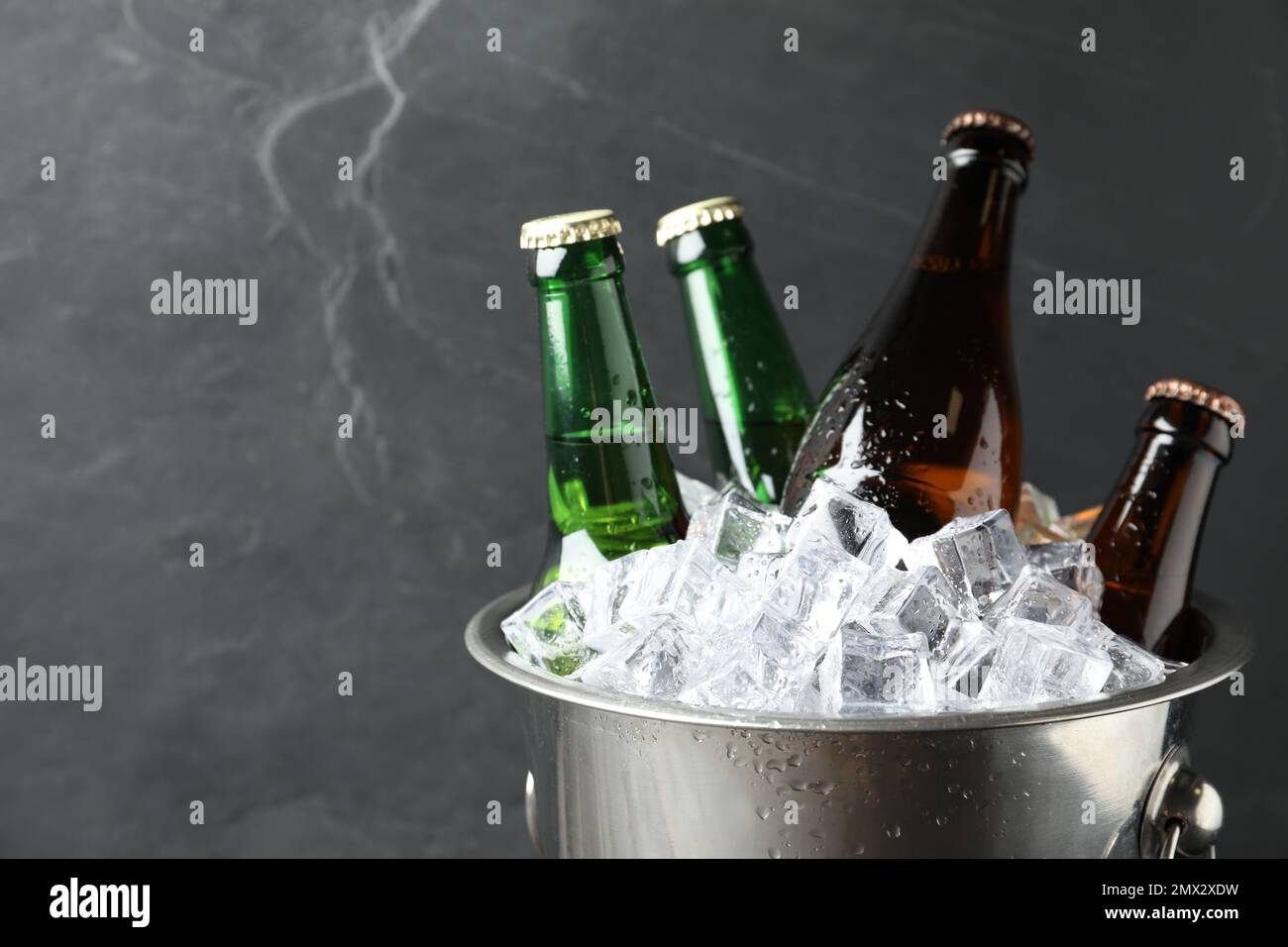 Metal bucket with beer and ice cubes on grey background, closeup. Space ...