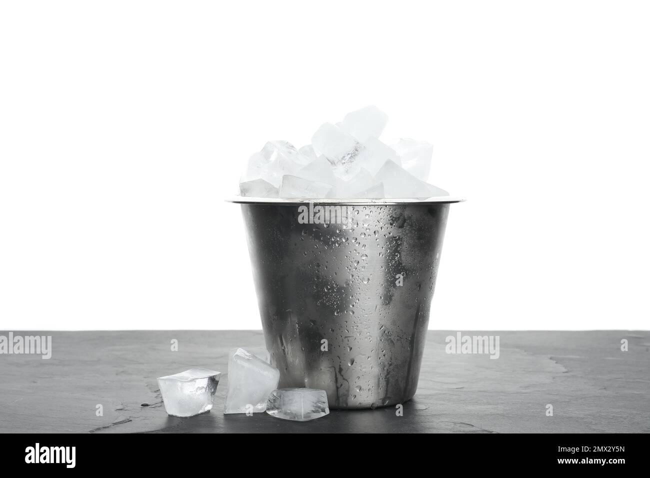 Metal bucket with ice cubes on table against white background Stock ...