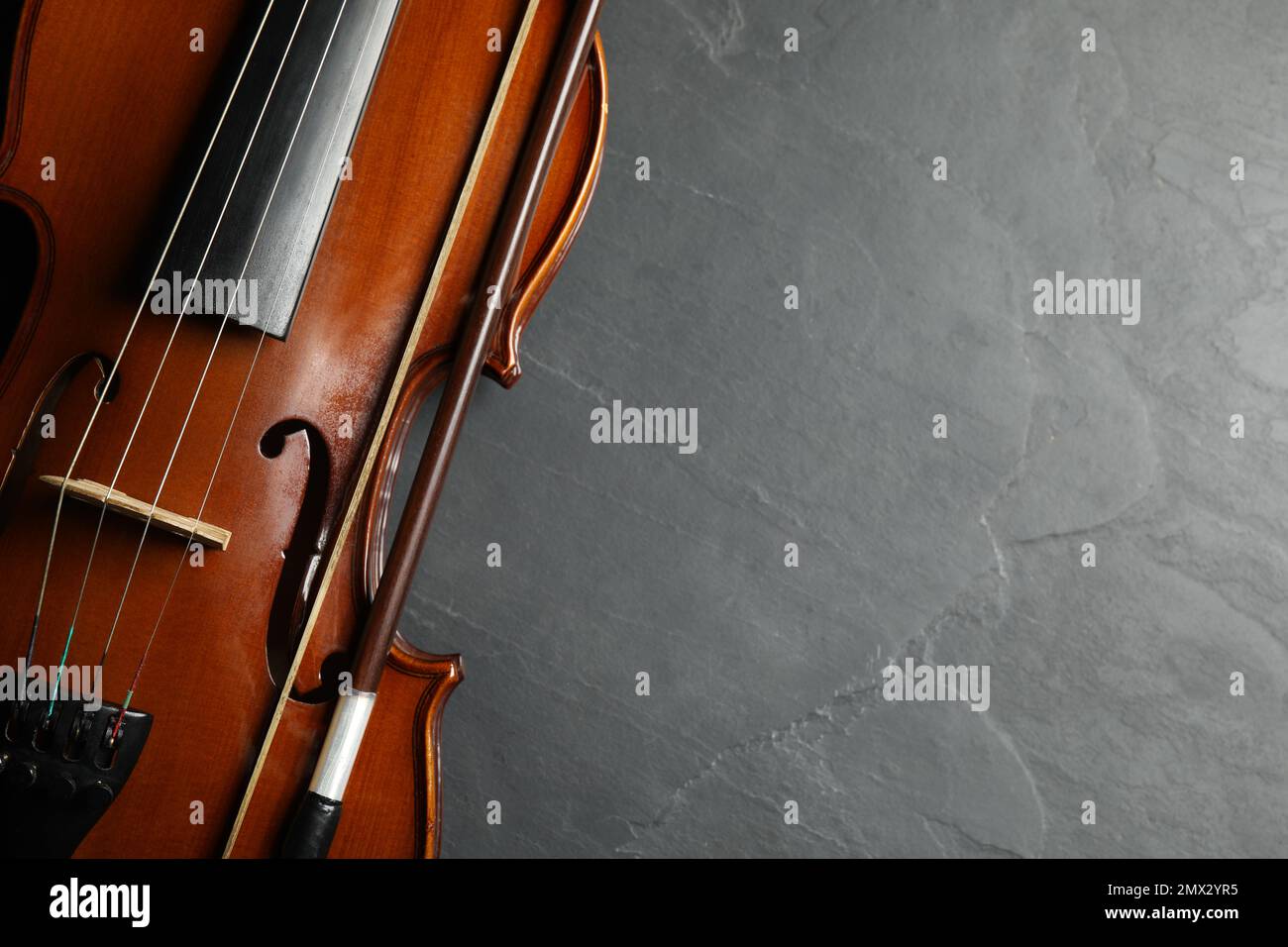 Classic violin and bow on grey stone background, closeup. Space for ...