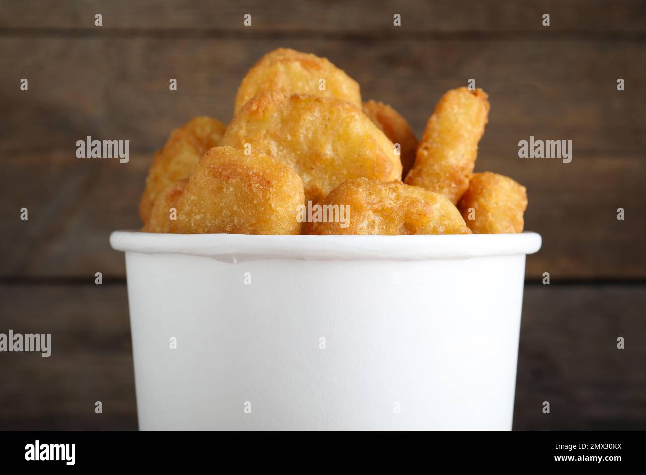 Bucket with tasty chicken nuggets on wooden background, closeup Stock ...