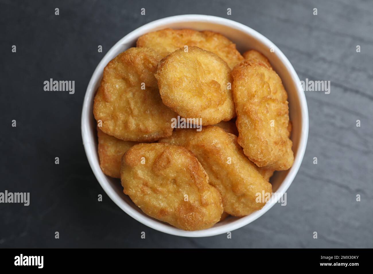 Bucket with tasty chicken nuggets on black table, top view Stock Photo ...