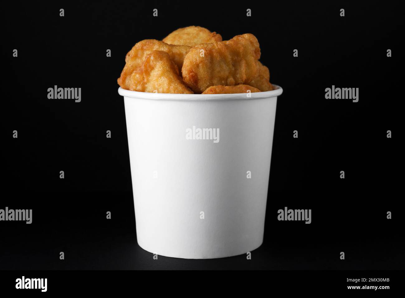 Bucket with delicious chicken nuggets on black background Stock Photo ...