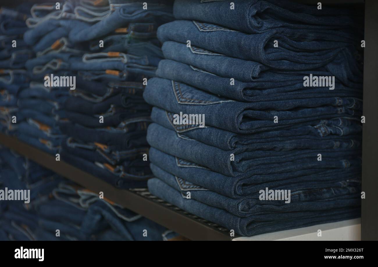Collection of stylish jeans on shelves in shop Stock Photo - Alamy