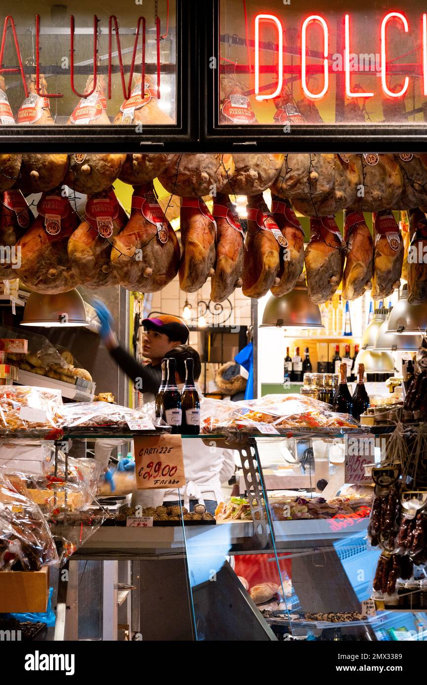 young man arranging hams in a traditional delicatessen in the center of ...