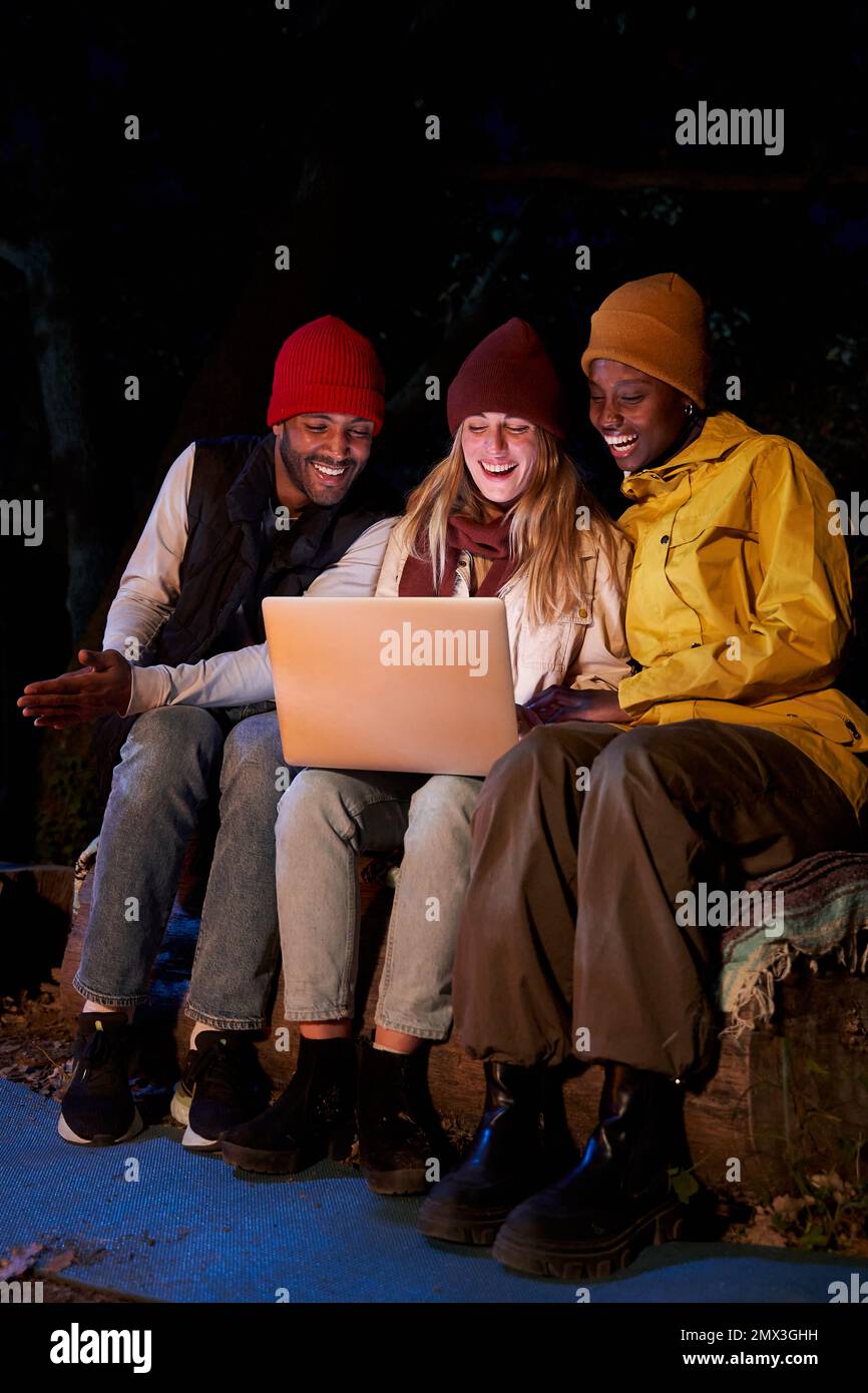 Three cheerful Mixed race Friends Using computer, sitting together at ...