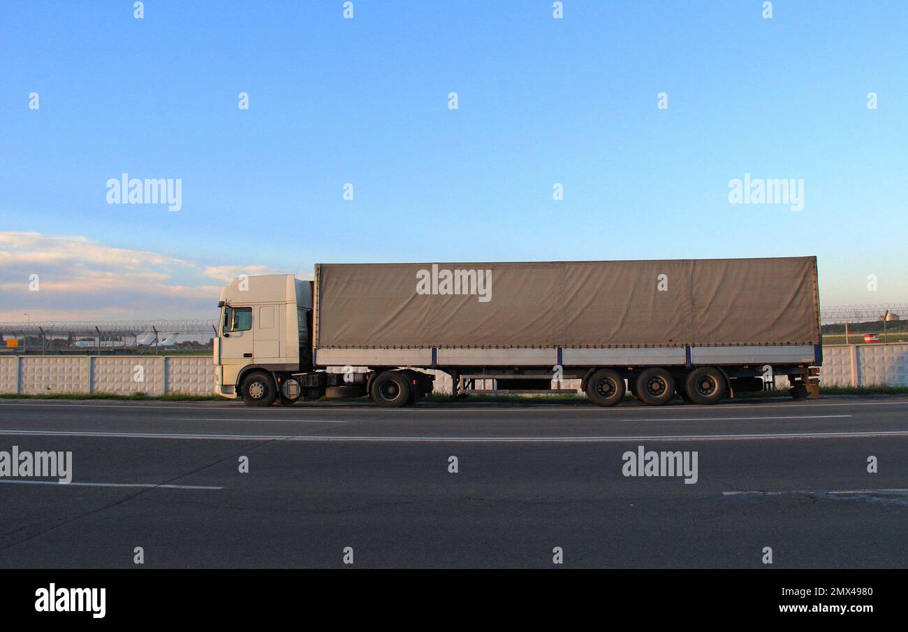 Long truck on a highway near the fence of the transport airport with ...