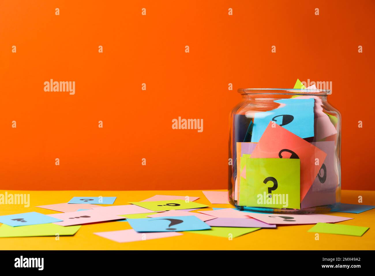 Colorful cards with question marks in glass jar on orange background ...