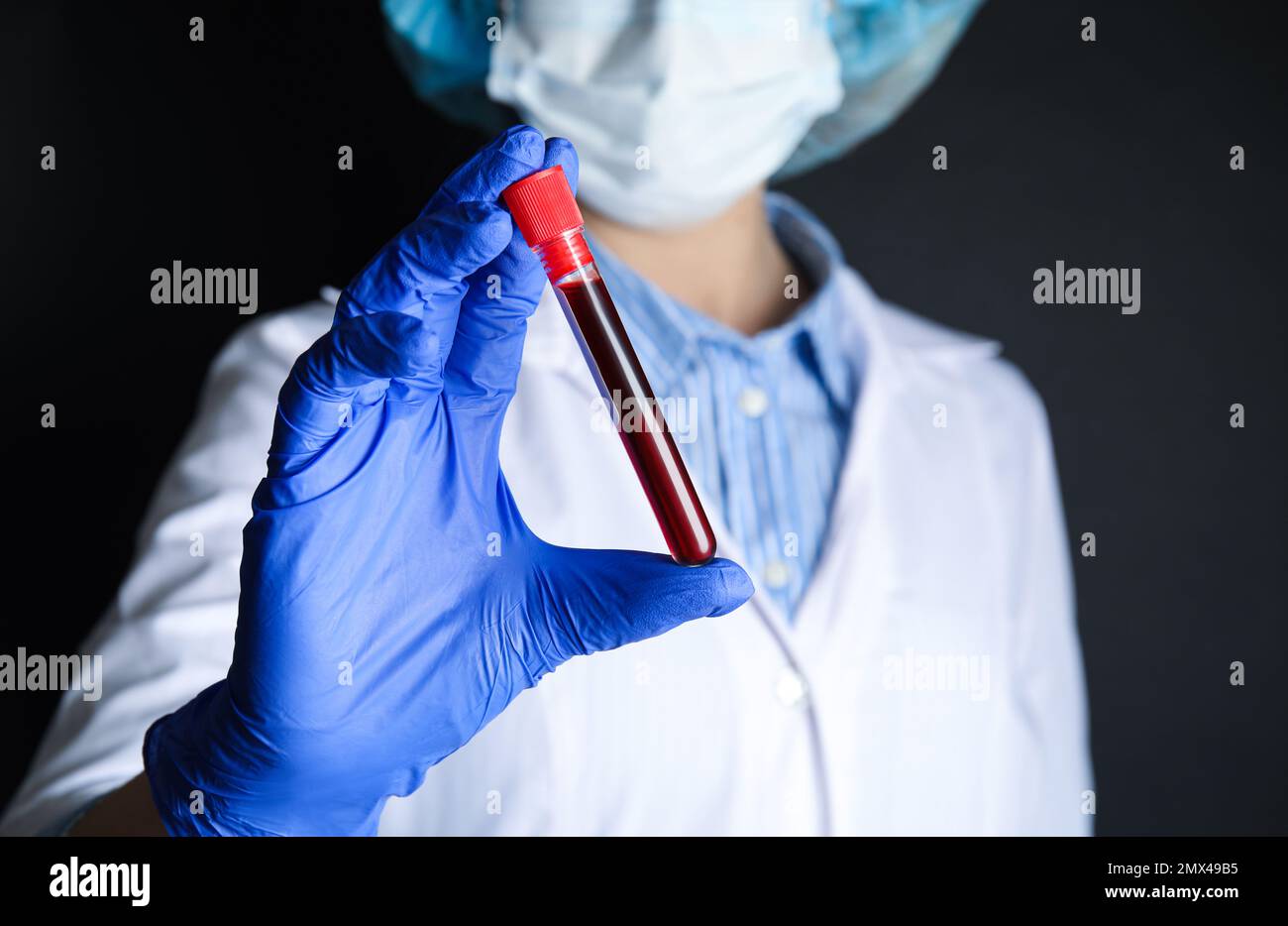 Scientist holding test tube with blood sample on black background ...