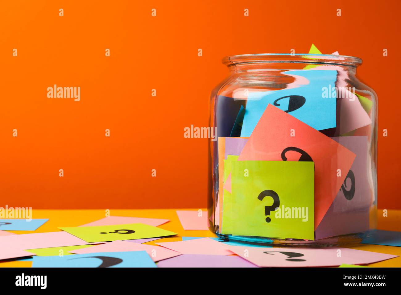 Colorful cards with question marks in glass jar on orange background ...