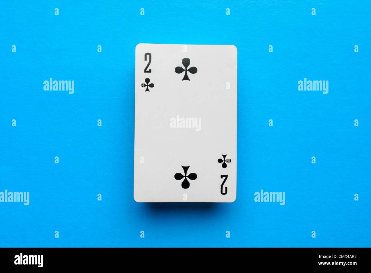 Playing card deuce of clubs on a blue background Stock Photo - Alamy