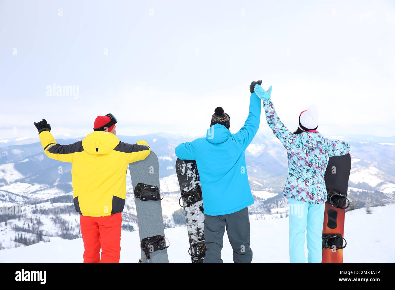 Friends with snowboards at mountain resort, back view. Winter vacation ...