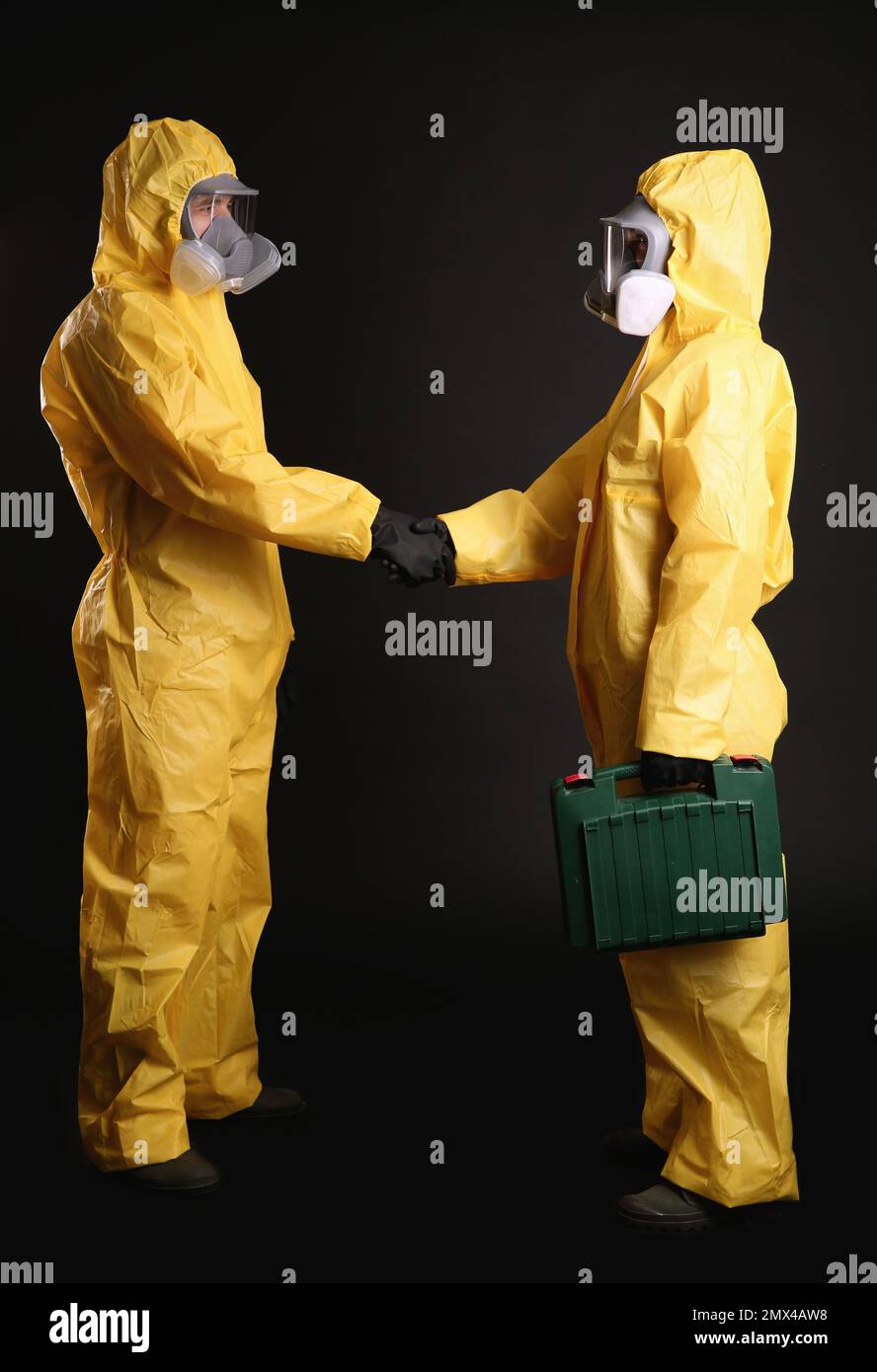 Man and woman in chemical protective suits shaking hands on black ...