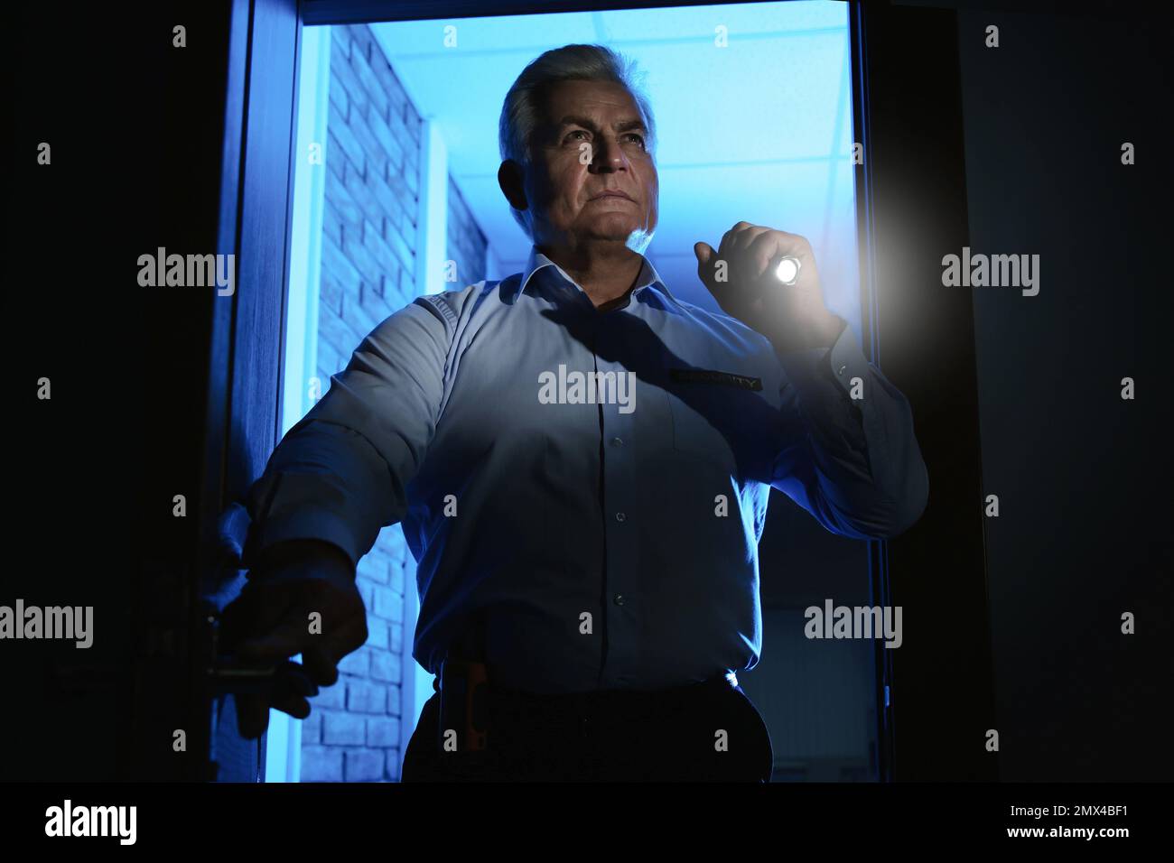 Professional security guard with flashlight checking dark room Stock ...