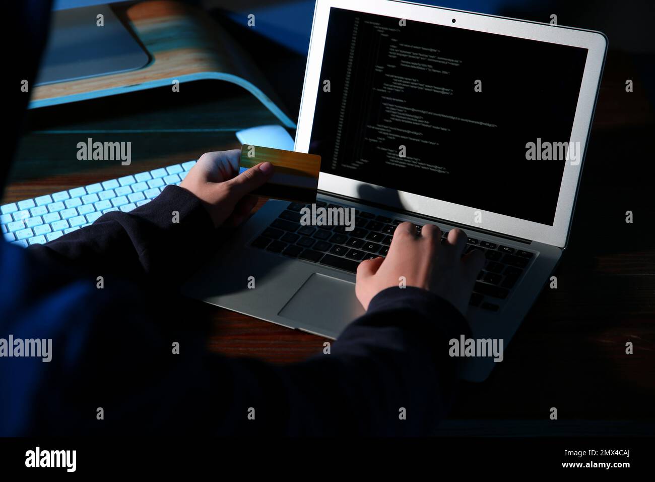 Hacker with credit card and laptop in dark room, closeup. Cyber crime ...