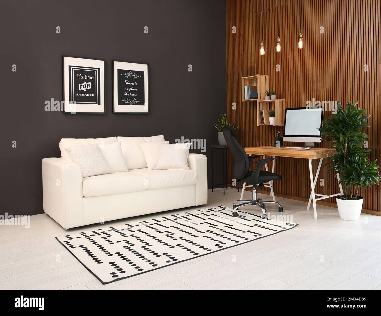 Comfortable workplace with computer near wooden wall in stylish room ...