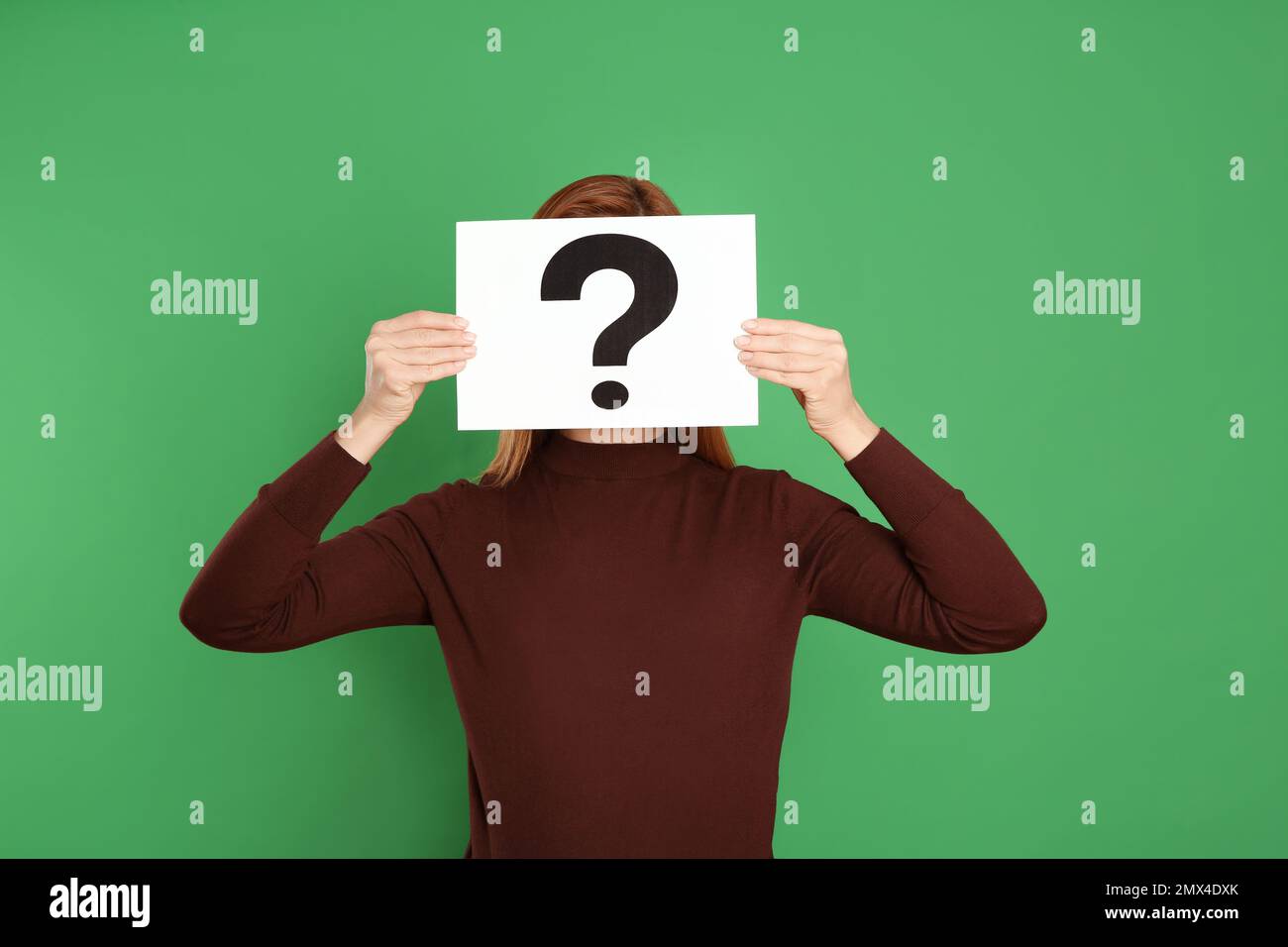 Woman holding question mark sign on green background Stock Photo - Alamy