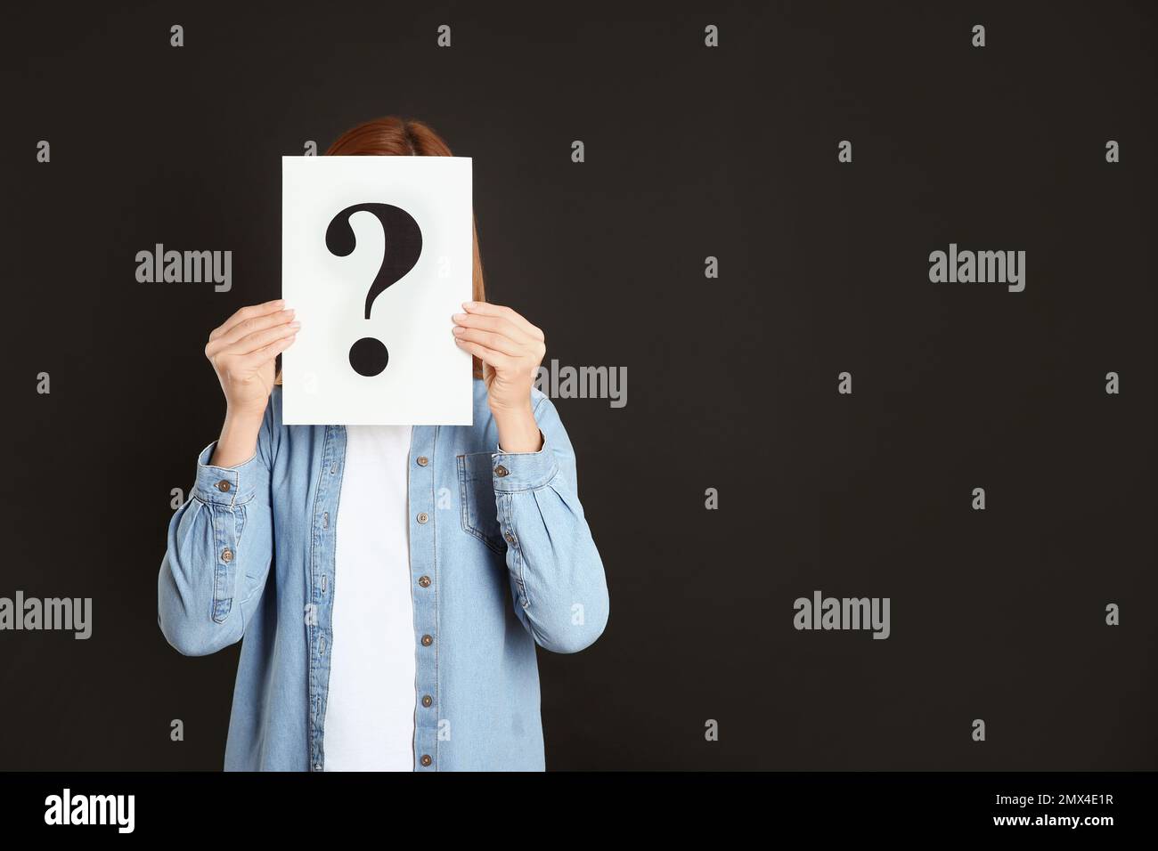 Woman holding question mark sign on black background. Space for text ...