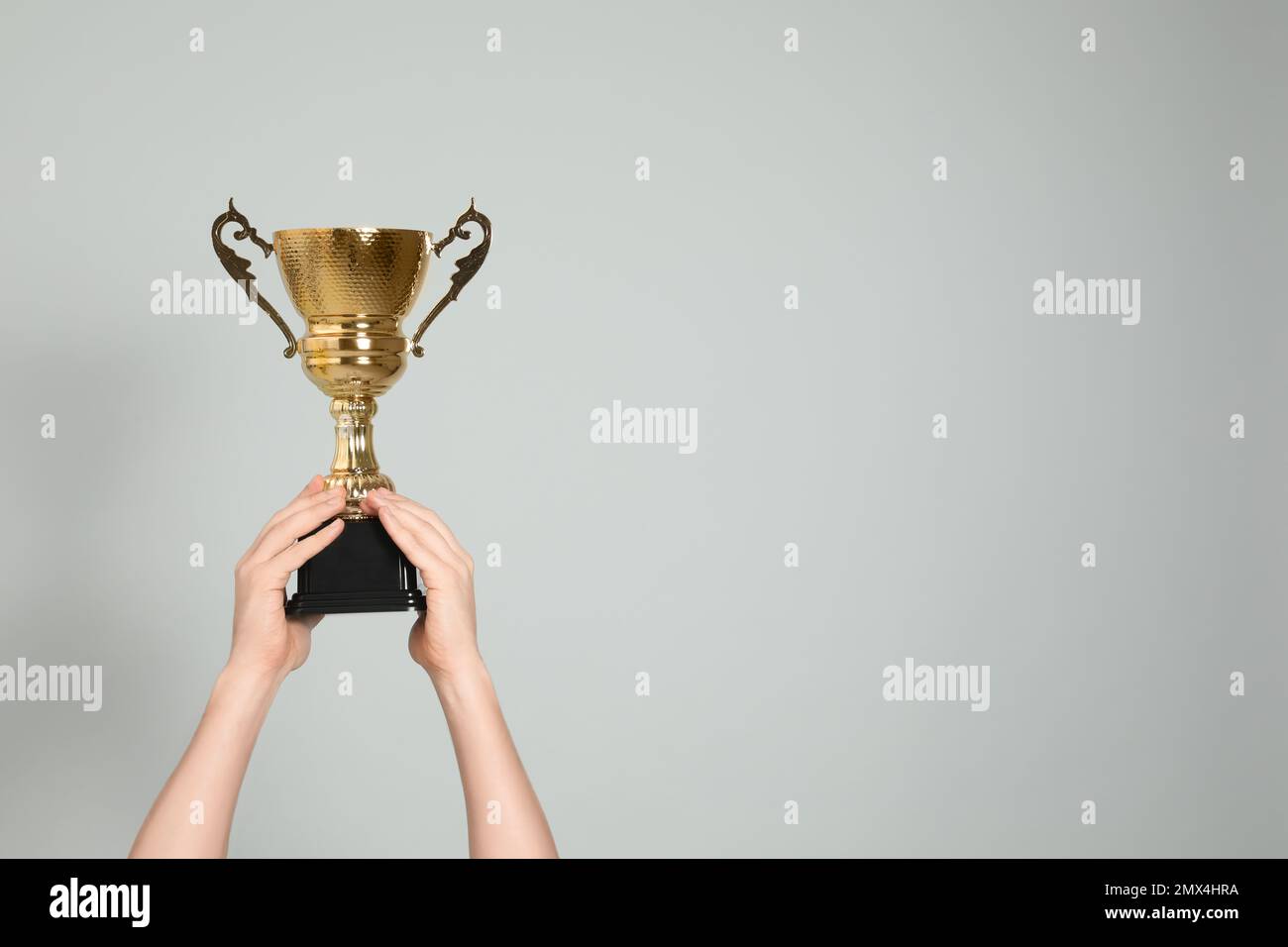 Man Holding Gold Trophy Cup On Light Grey Background Closeup Space