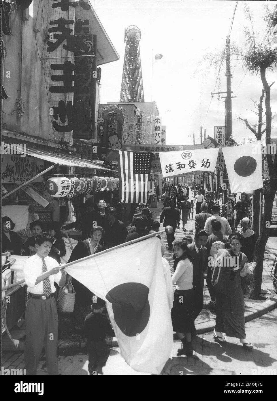 A Japanese shop keeper prepares to hoist a large Japanese flag on a ...